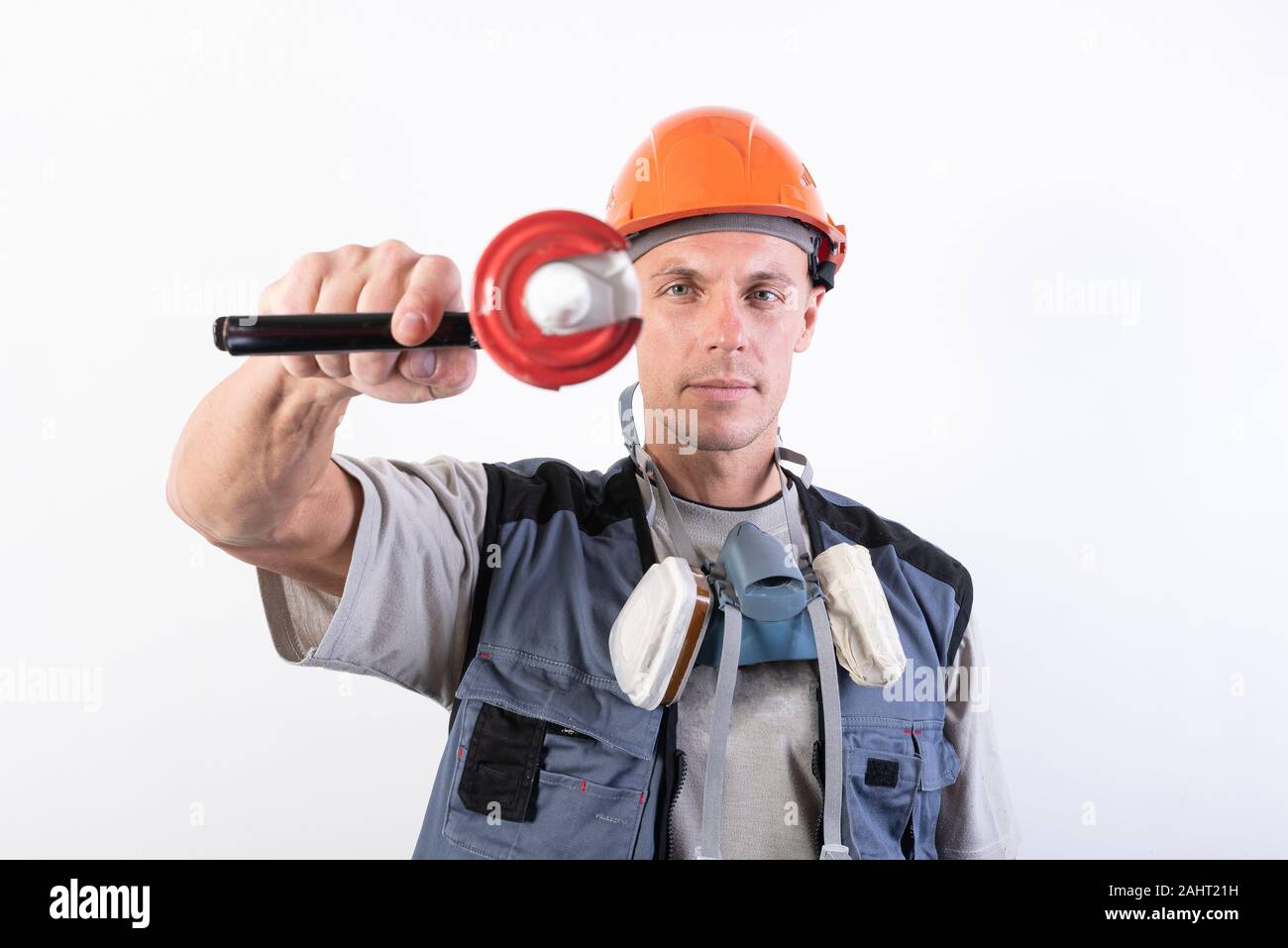 Builder with sealant. In work clothes and hard hat. On a light gray ...