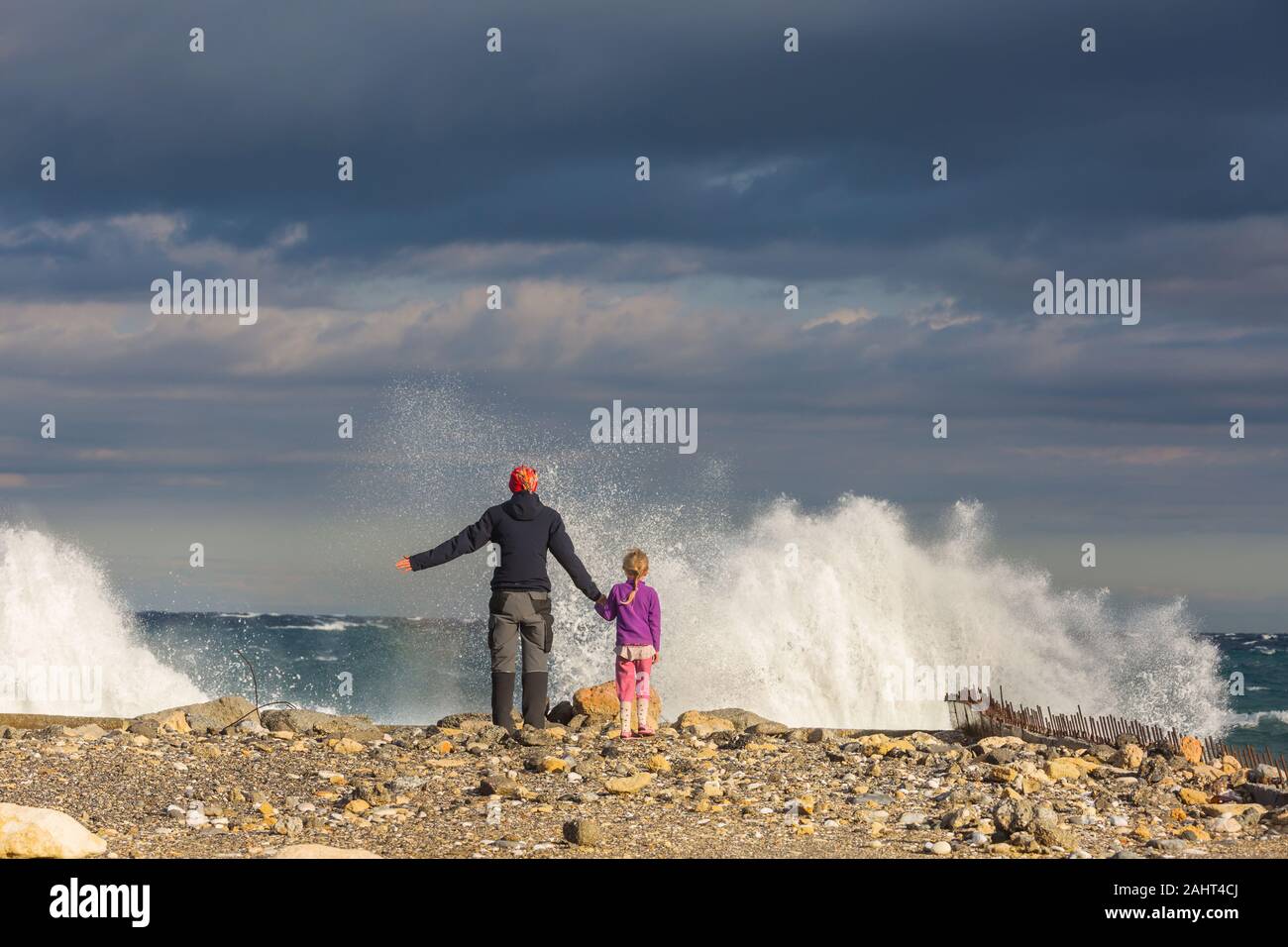 Man standing against the sea on a pier with big wave beating with ...