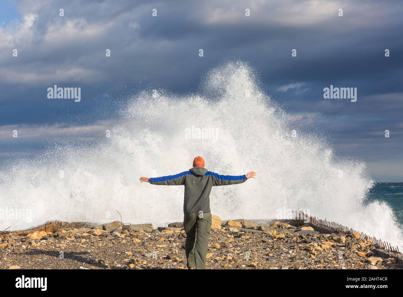 Man standing against the sea on a pier with big wave beating with ...