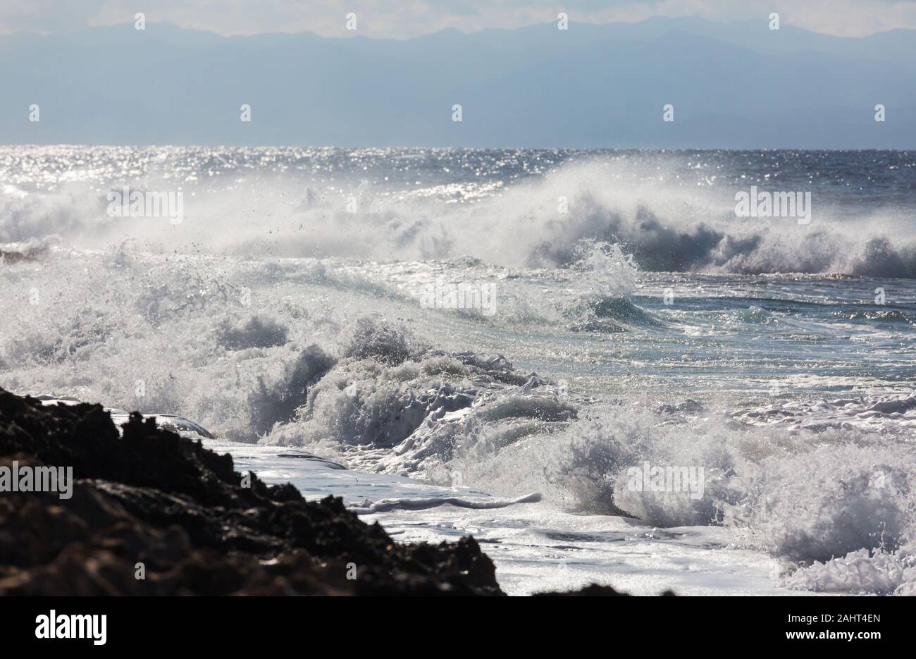Man standing against the sea on a pier with big wave beating with ...