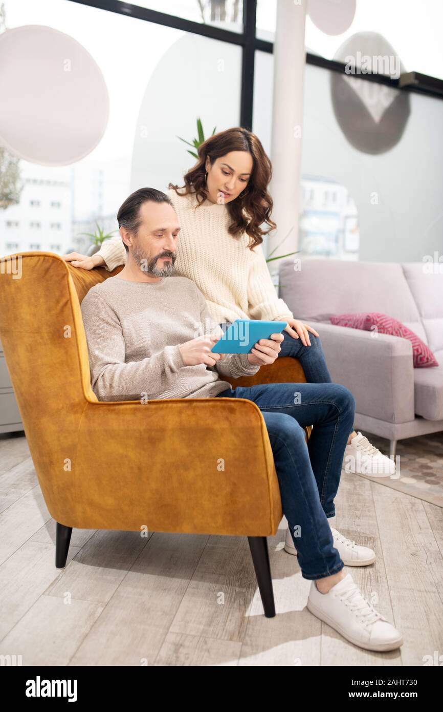 Couple spending their time in the furniture salon looking models online ...