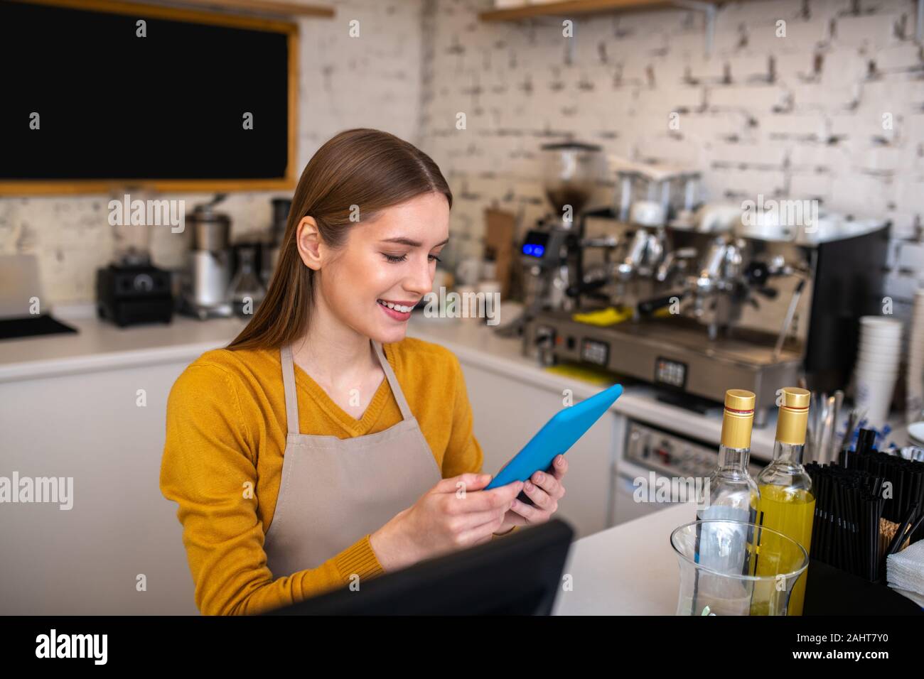 Smiling cafe employee using the tablet for her work Stock Photo - Alamy