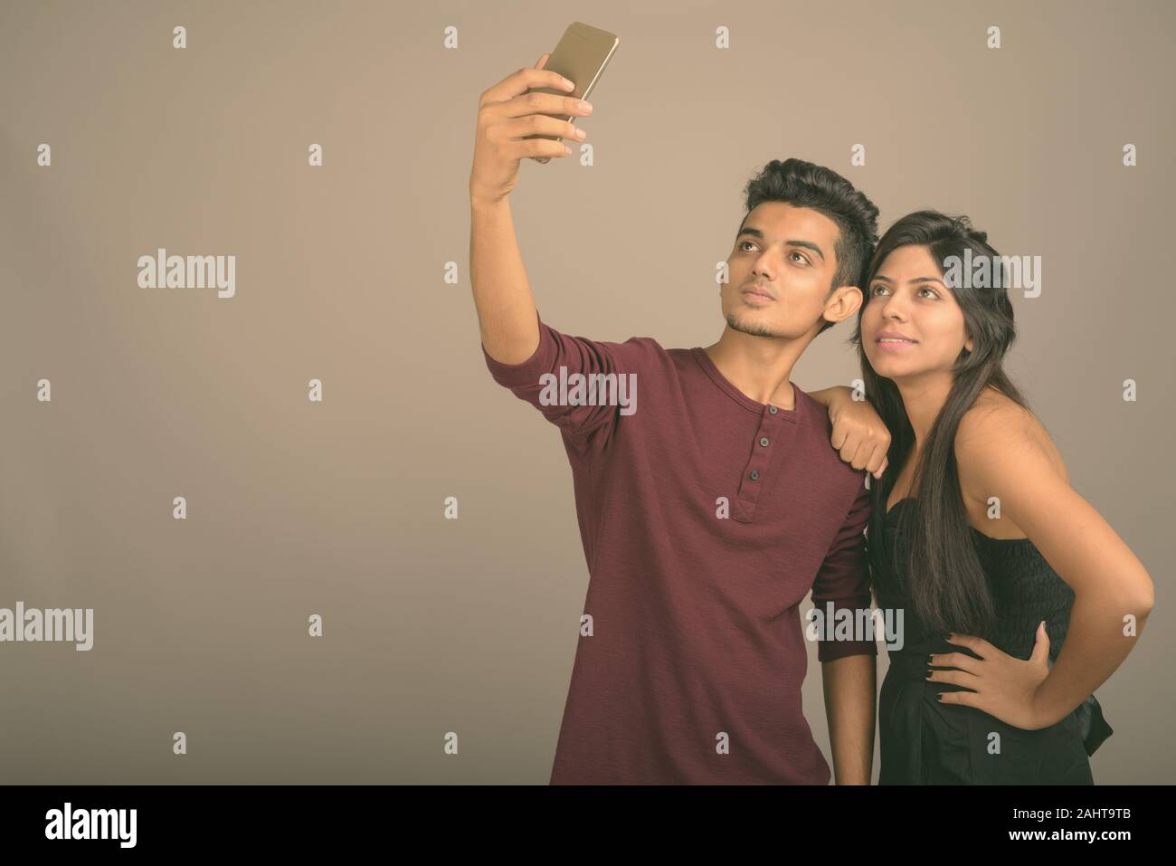 Studio shot of young Indian man and young Indian woman together against ...
