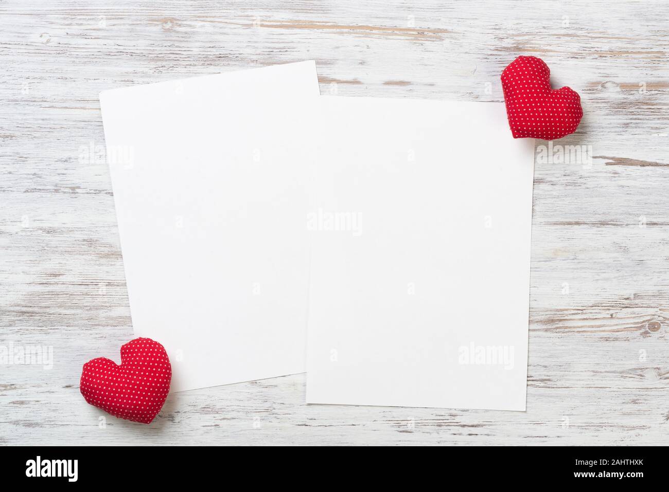 Blank sheets of paper and red love hearts on wooden table. View from ...