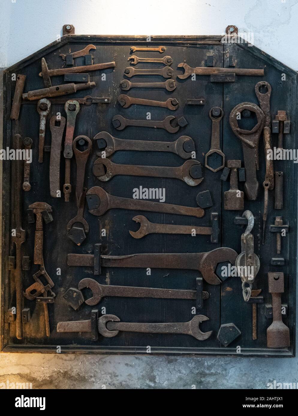 A wall mounted selection of old spanners, wrenches and other tools ...