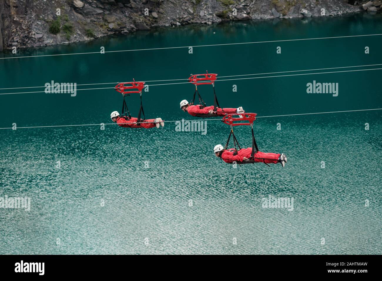 Three people on the Velocirty 2 zip lines at Zip World Penrhyn Quarry ...