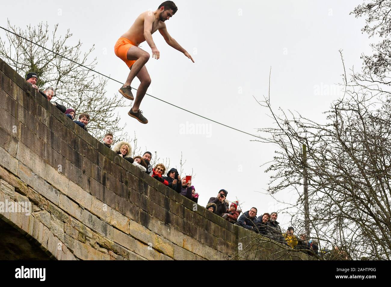 A charity competitor jumps off of Okeover Bridge into the River Dove ...