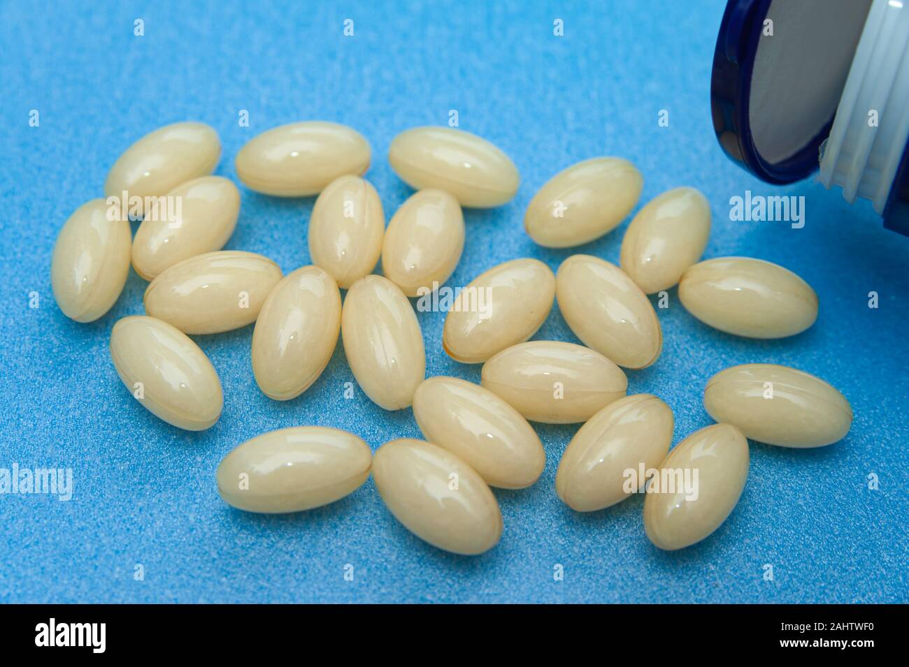 Yellow softgel supplement on blue background. Horizontal shot Stock ...