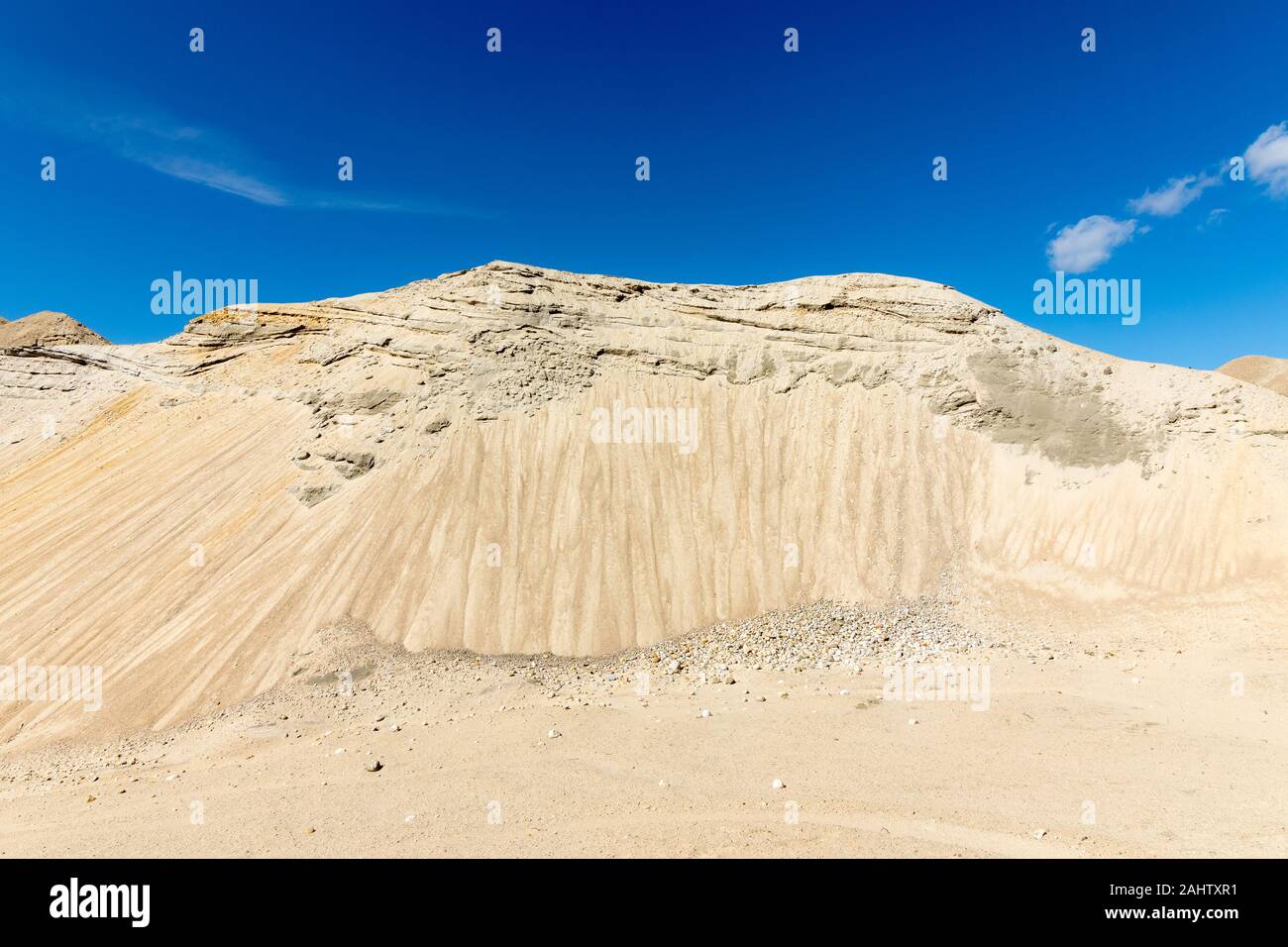 Sand in a big sand pit, with blue sky and white clouds in the ...