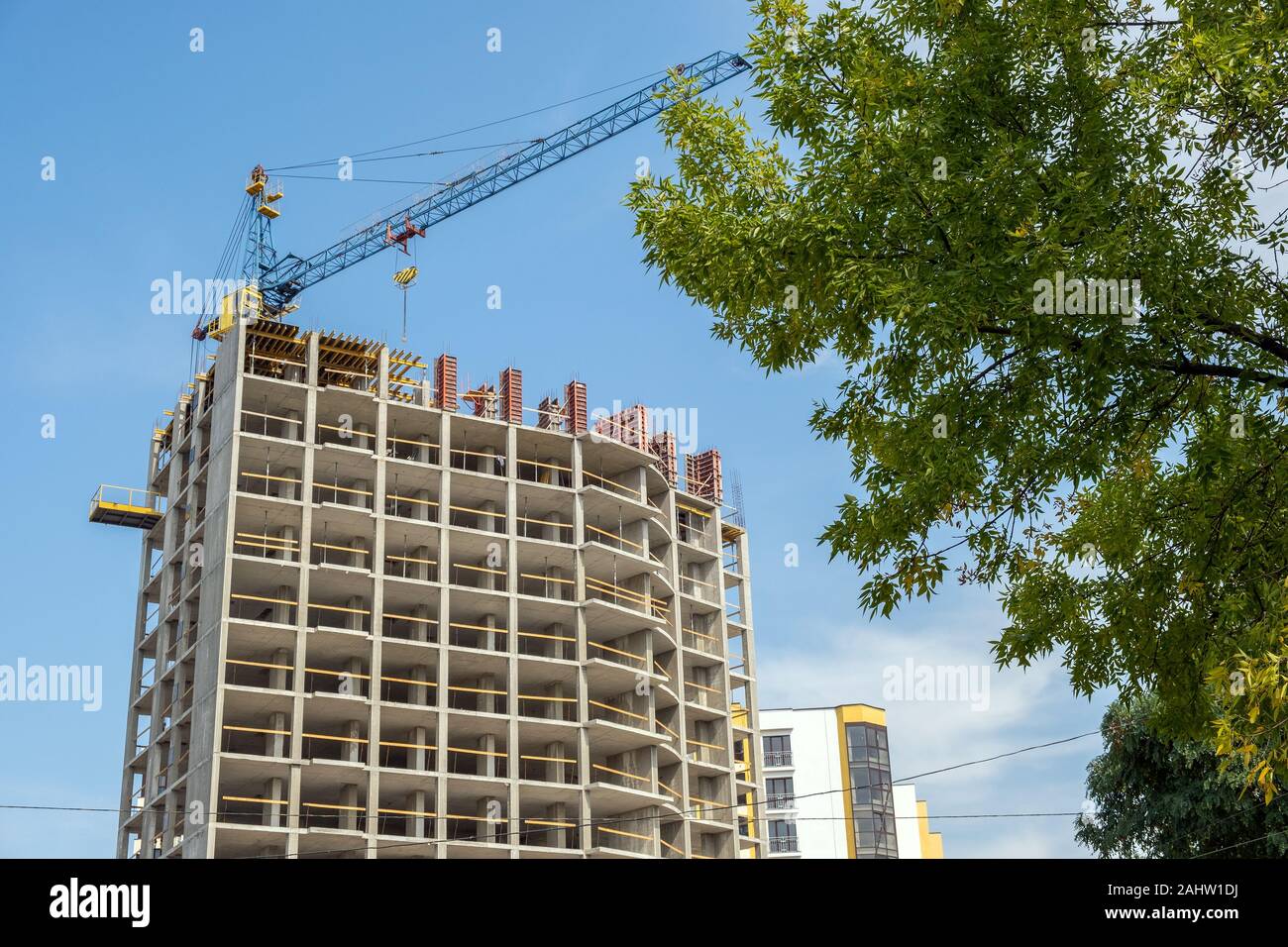 Concrete frame of tall apartment building under construction and tower ...