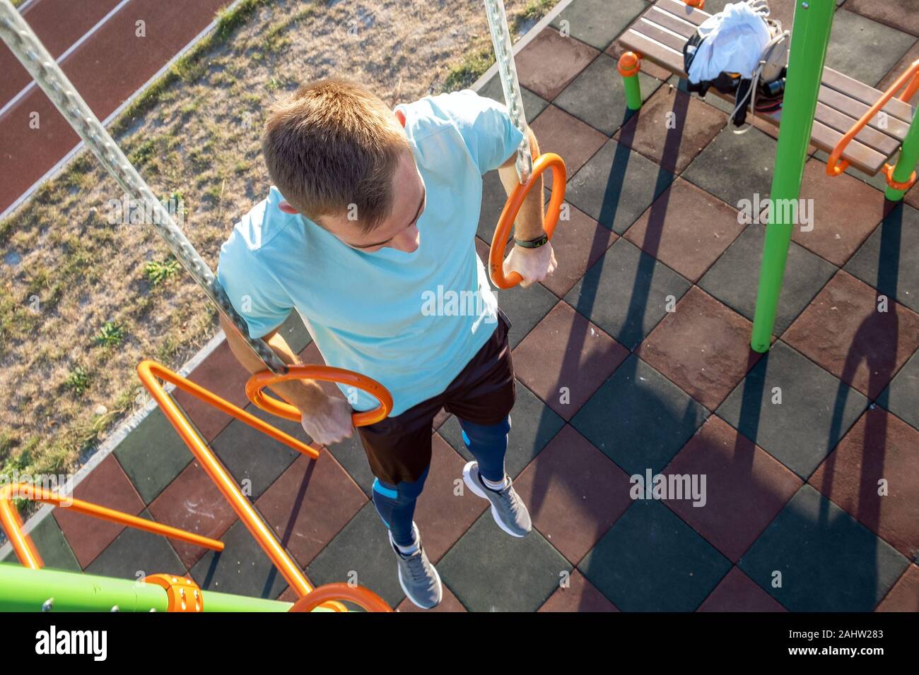 Young fit athlete working out at outdoor gym making dipping pull ups ...