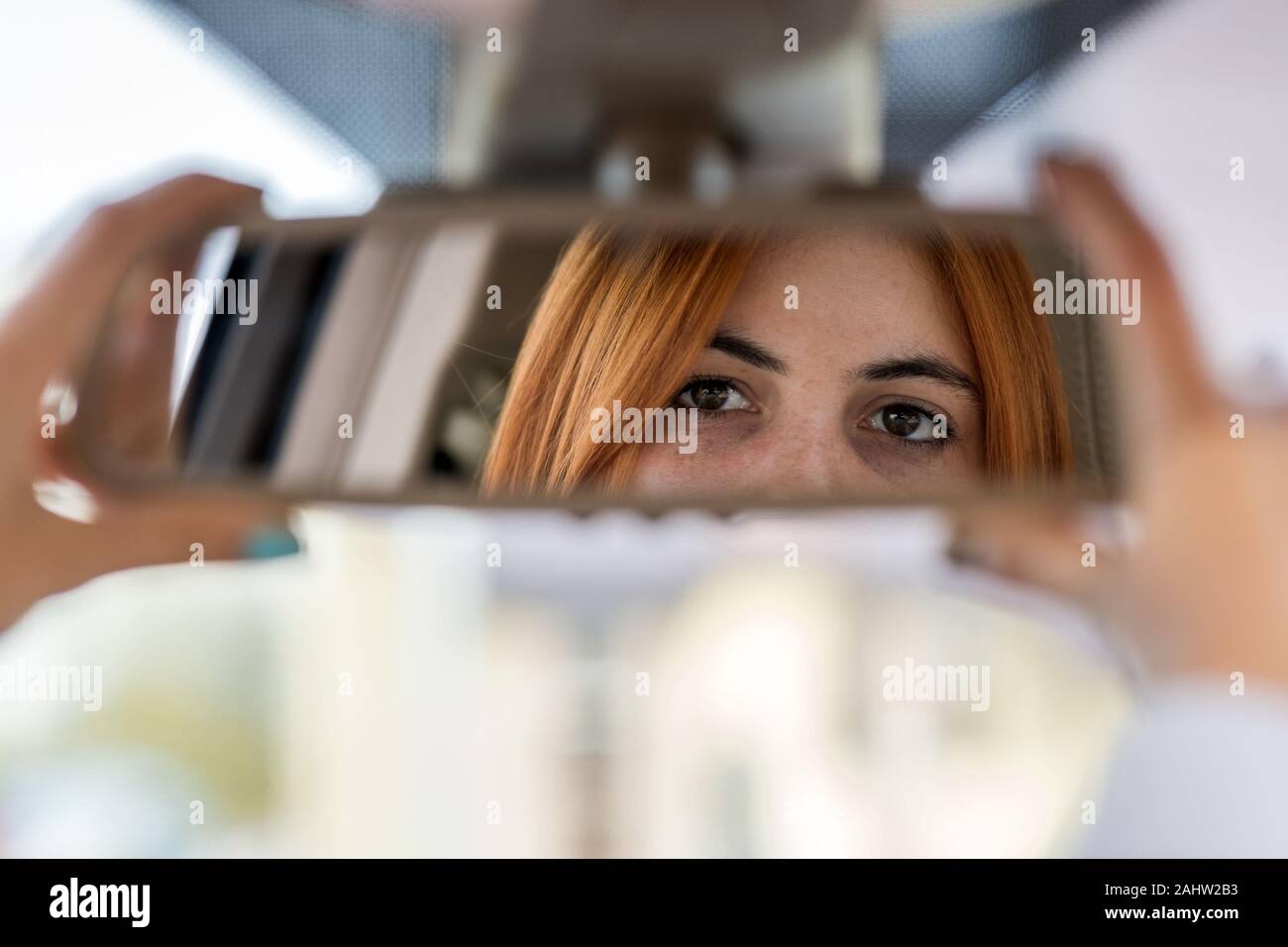 Young woman driver checking rear view mirror looking backwards while ...