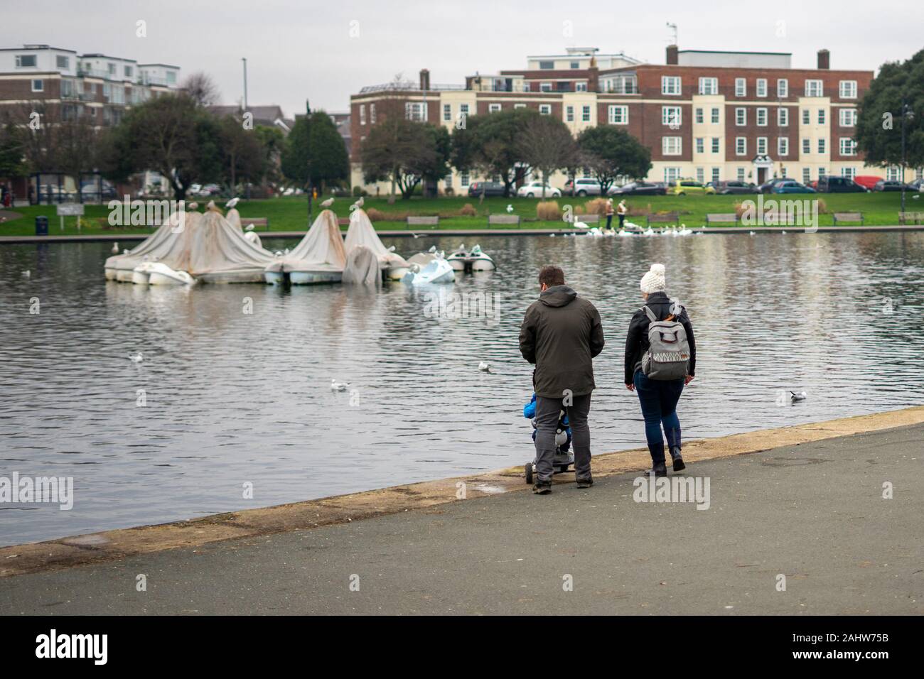A young family visiting a duck pond in the park on a winters day Stock ...