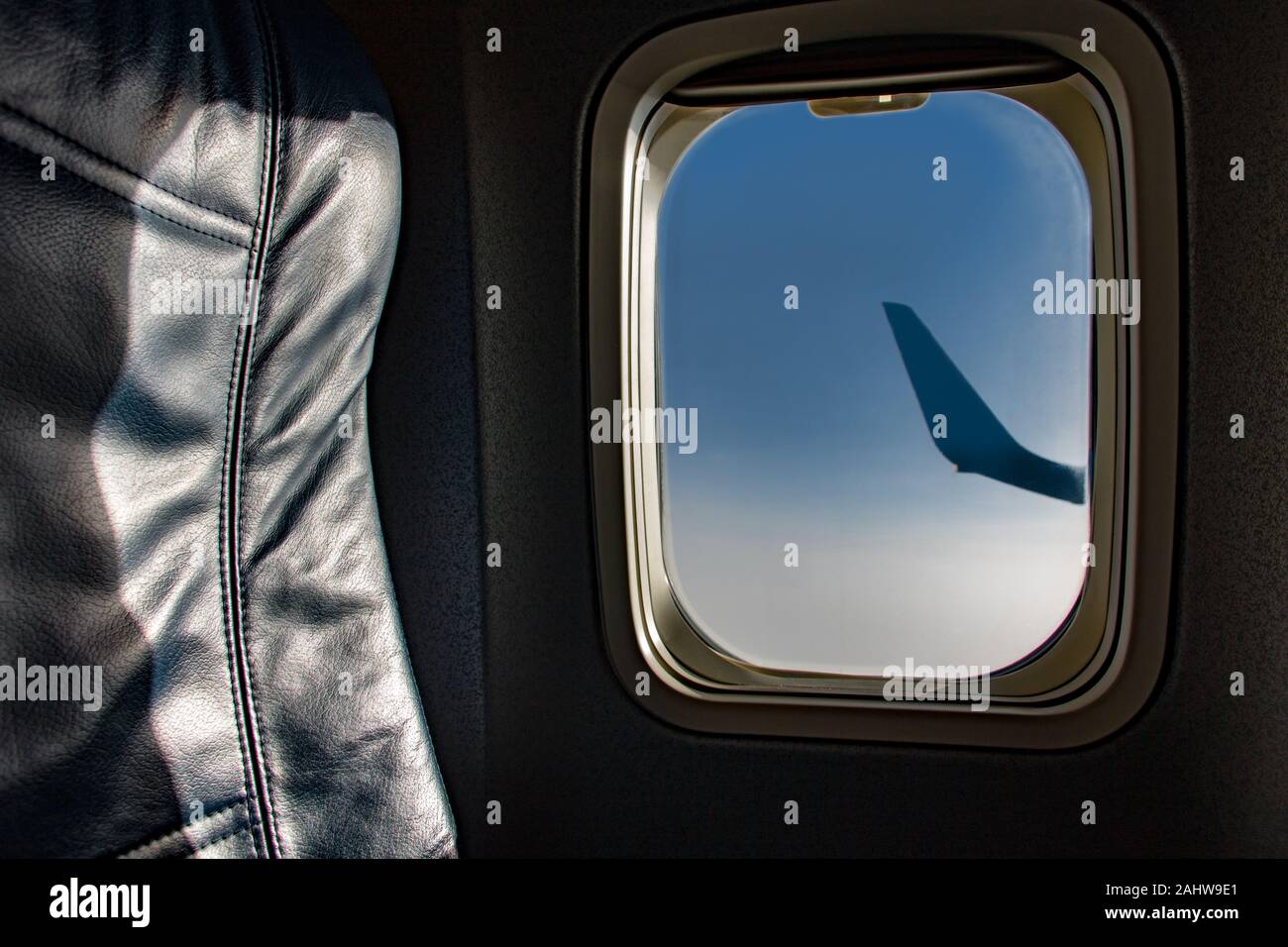 An empty leather chair in air plane. Blue seat beside window with blue ...