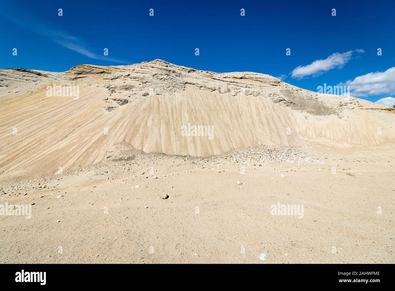 Sand in a big sand pit, with blue sky and white clouds in the ...