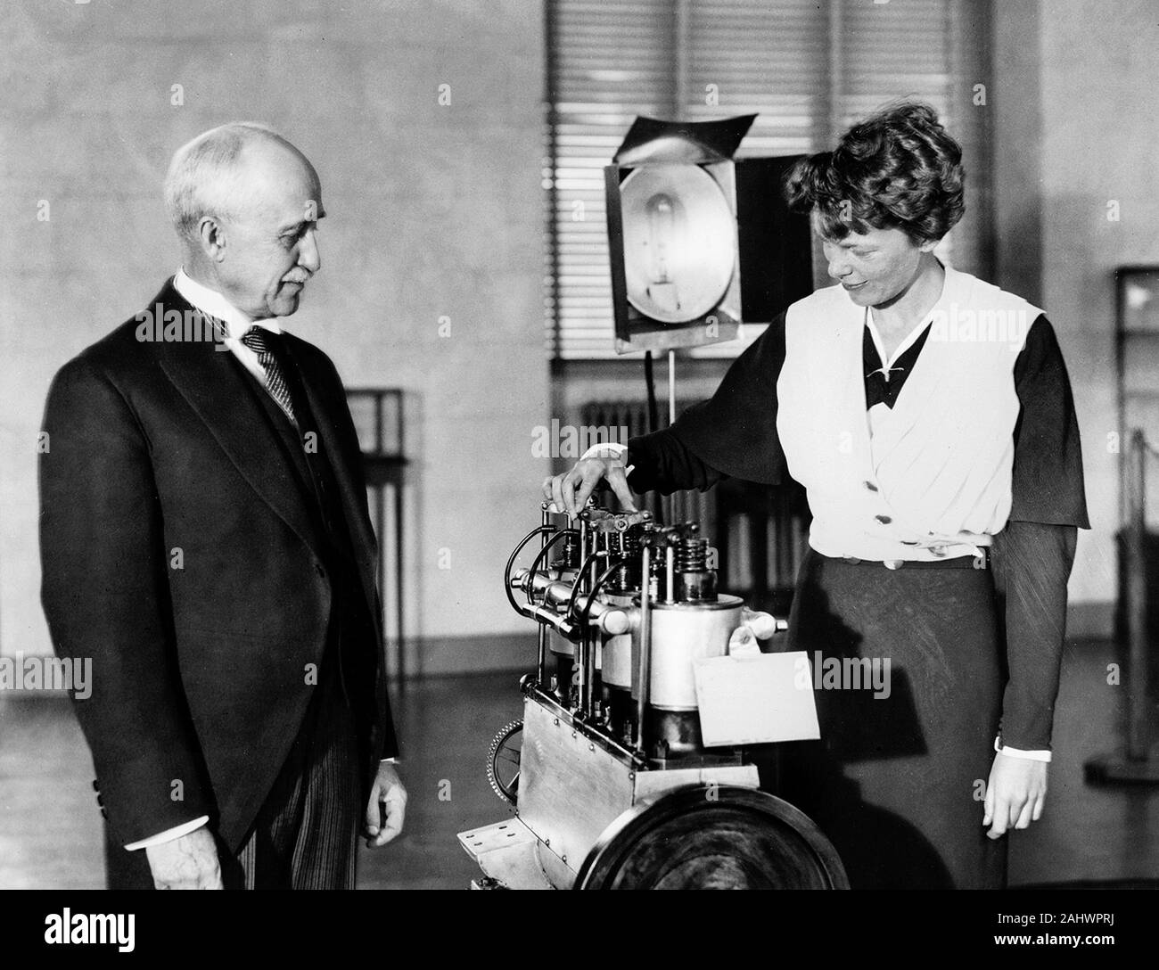Amelia Earhart and Orville Wright examining a 4-cylinder vertical ...