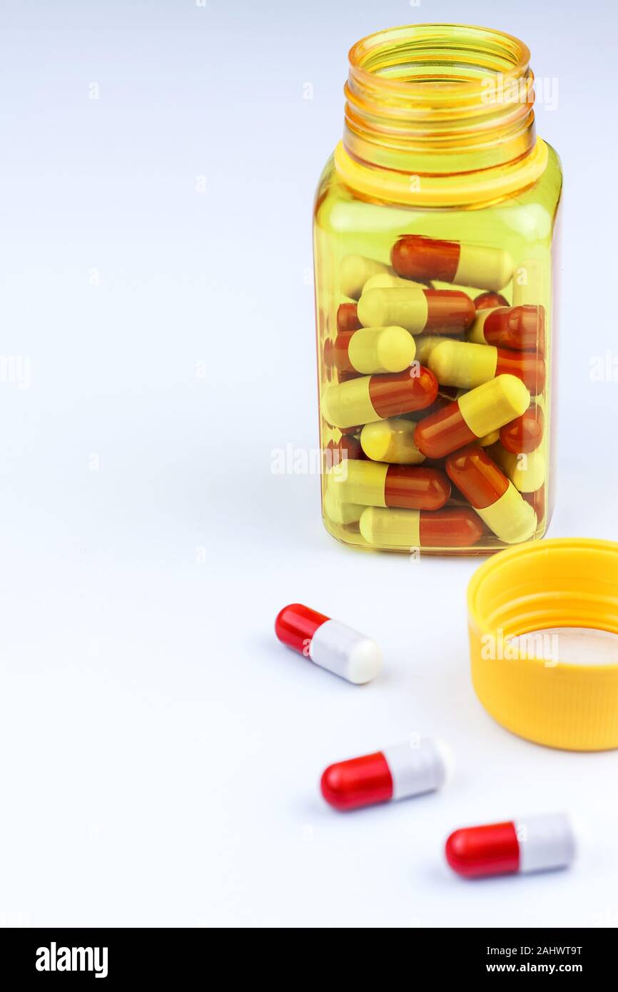 Red-white tablets on white background. Medicines in yellow jar ...