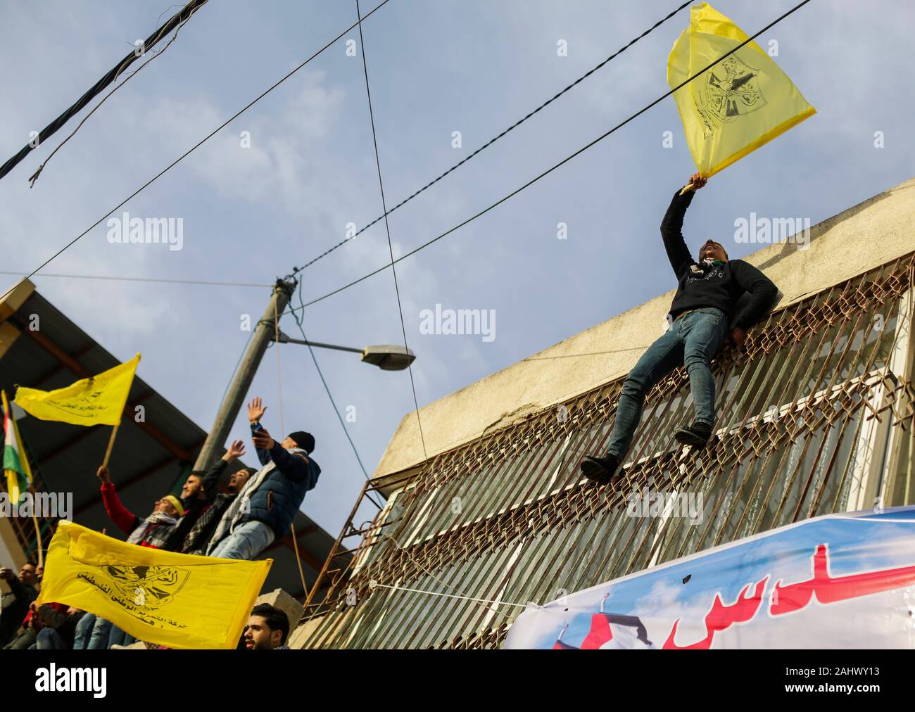 Palestinian on top of a building waves a yellow Fatah flag during a ...