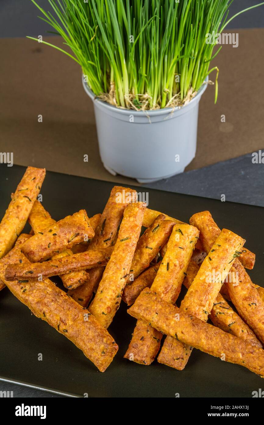 Plate of stacked cheese straws with chive plant behind, portrait Stock ...