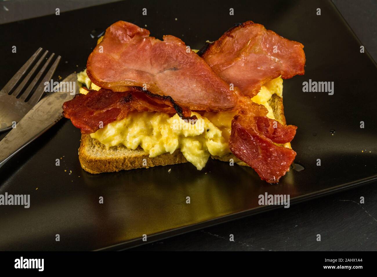 Elevated view of Rashers of bacon and scrambled egg on toasted brown ...