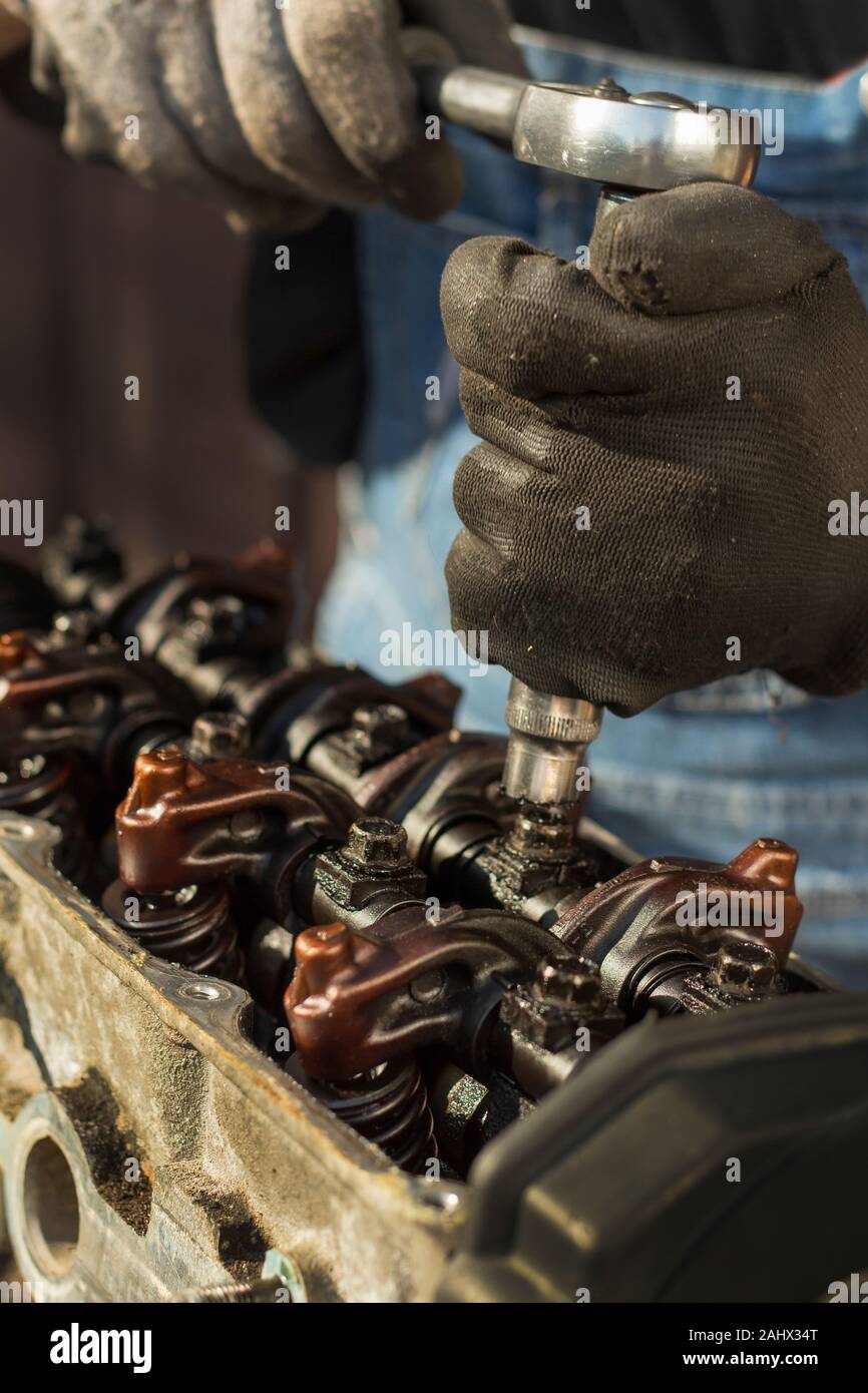 The mechanic's hand unscrews the screw in the engine with a socket ...