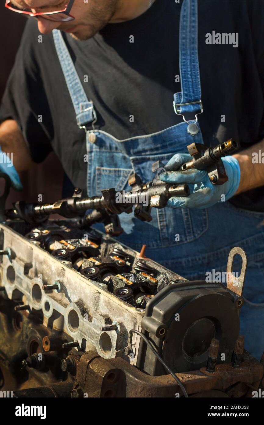 Car mechanic during engine overhaul. Unscrews and disassembles the ...
