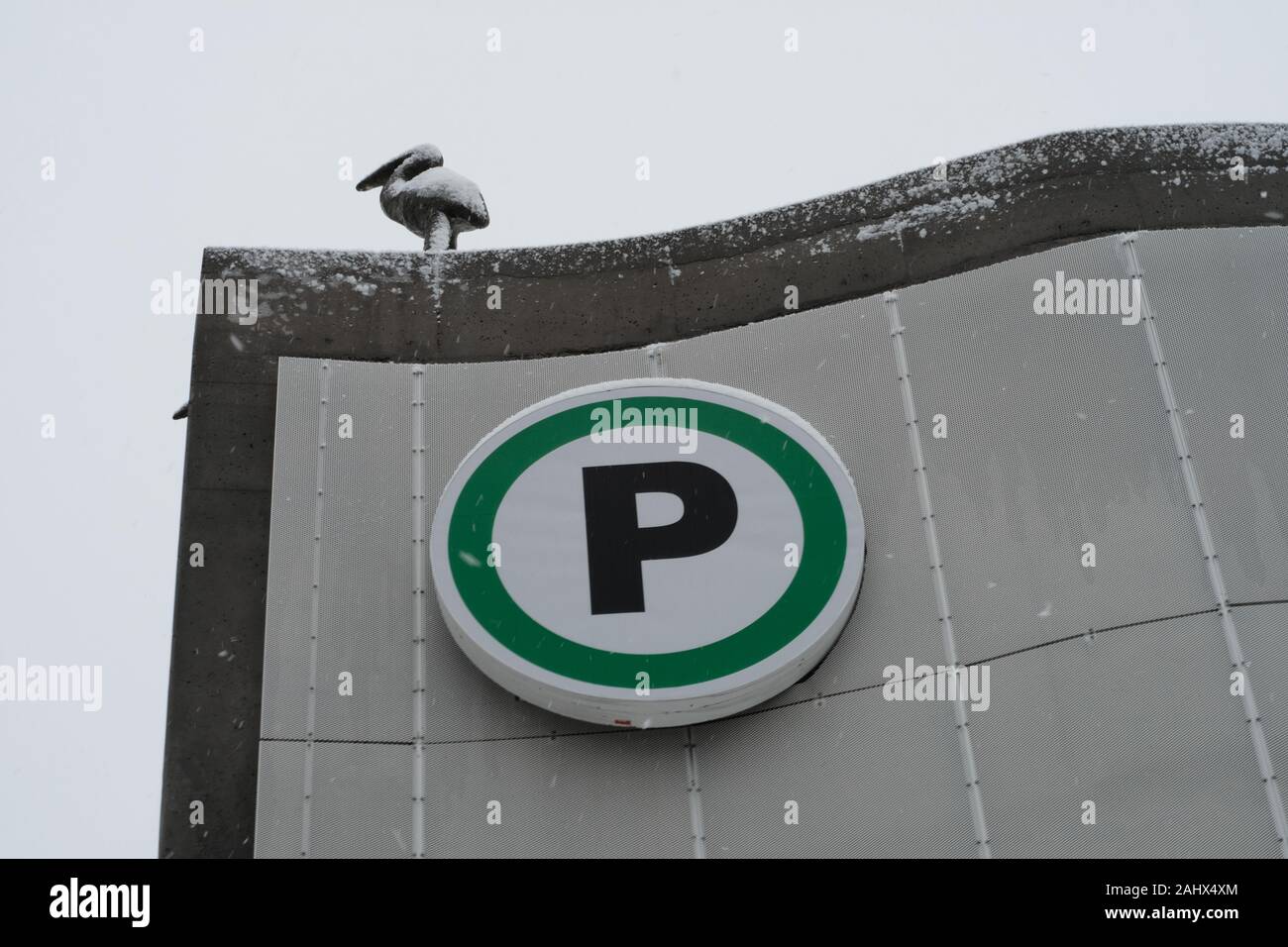 Concrete sculpture of a crane on the edge of the roof above a green and ...