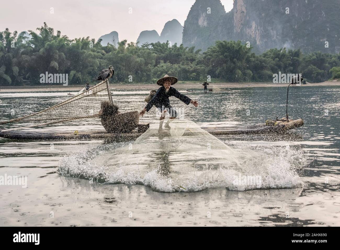 Cast net hits the water creating myriad water droplets, Li River near ...