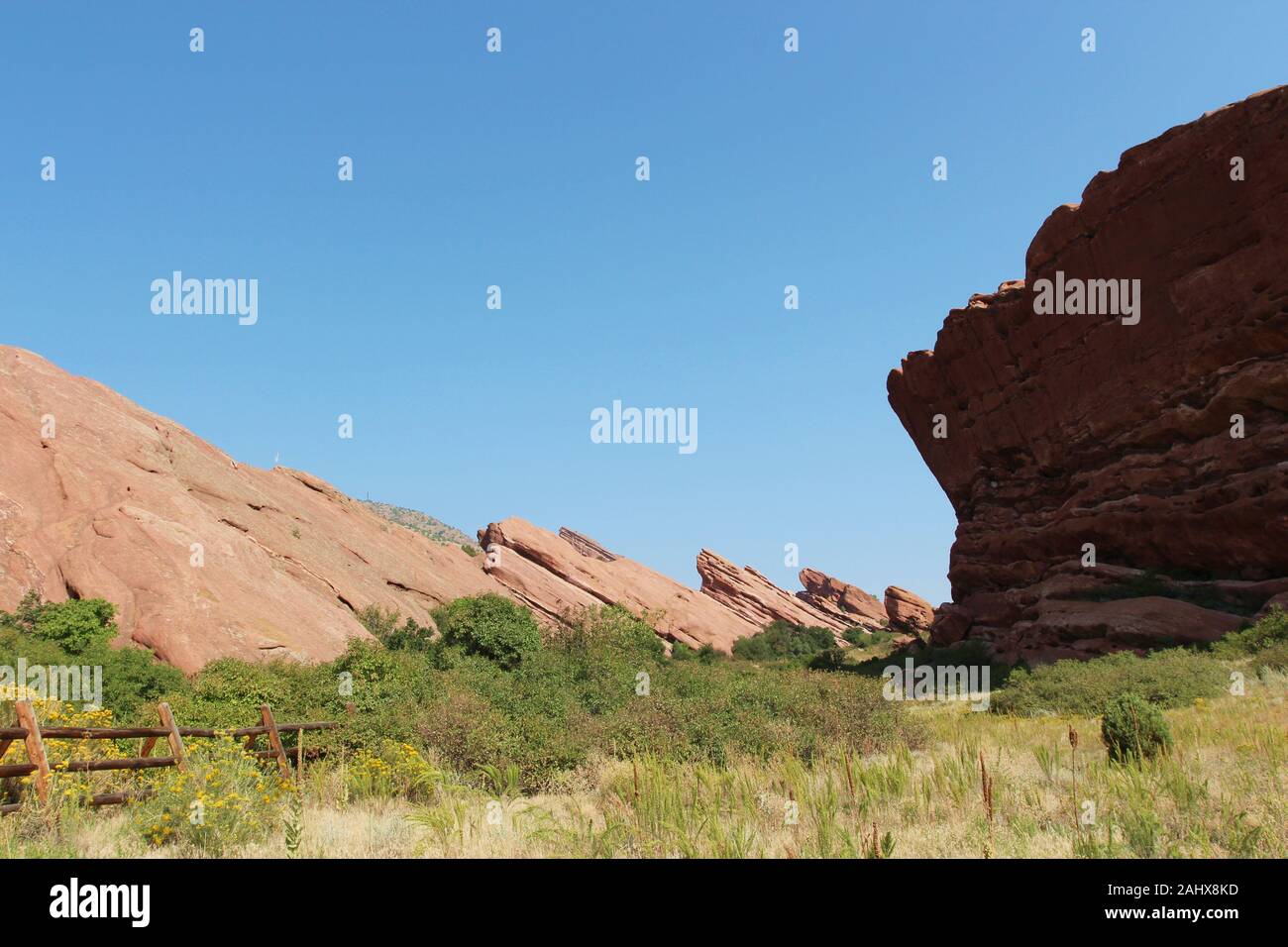 Red rock formations behind a wood fence, in front of a mountainside, on ...
