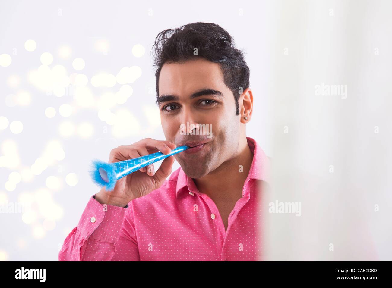 Portrait of a young man with a party blower Stock Photo - Alamy