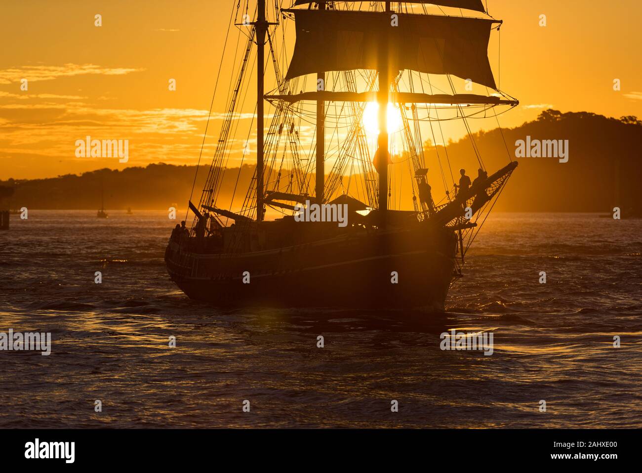 Silhouette of old ship with sails against colorful orange sunset sky on ...