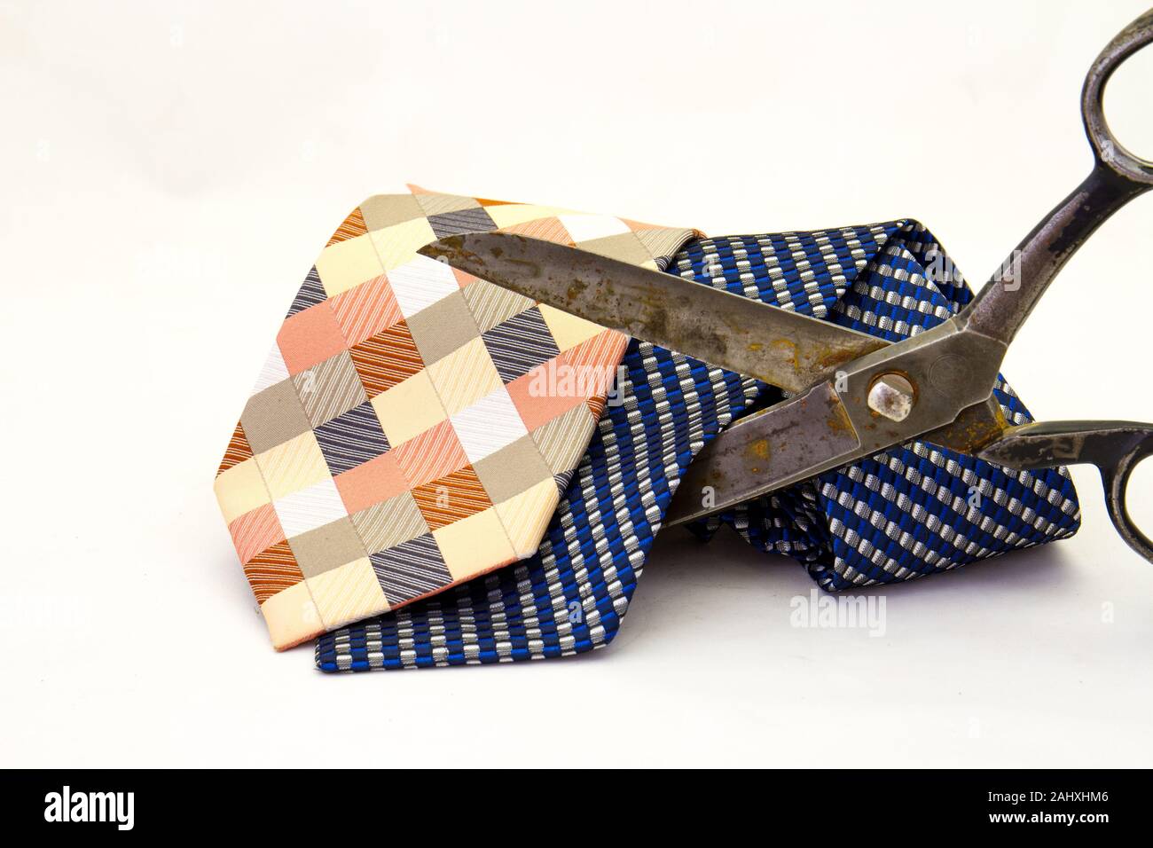 Two colourful ties being cut by a pair of old and large black scissors ...