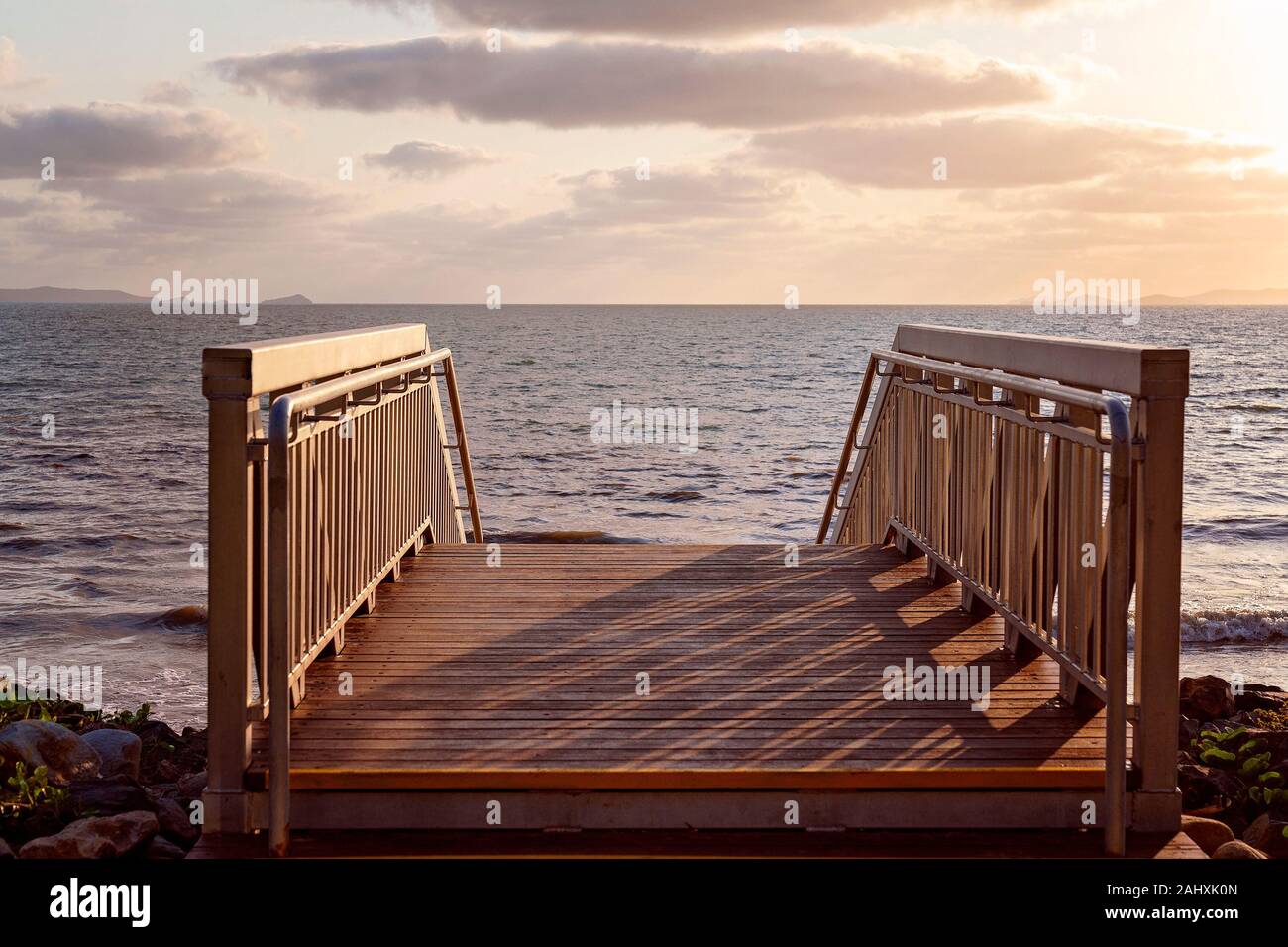 Timber stairs with safety railings leading down to the beach, with sand ...