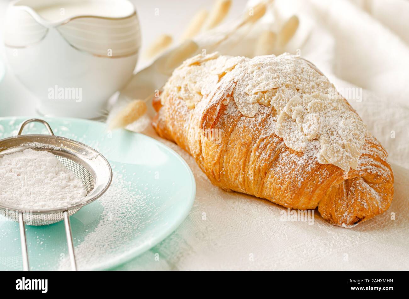 Breakfast menu of milk, croissant with powdered sugar and almond flakes ...