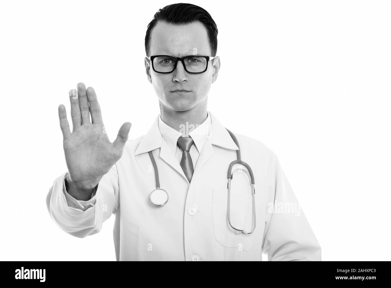 Studio shot of young handsome man doctor with stop hand gesture Stock ...