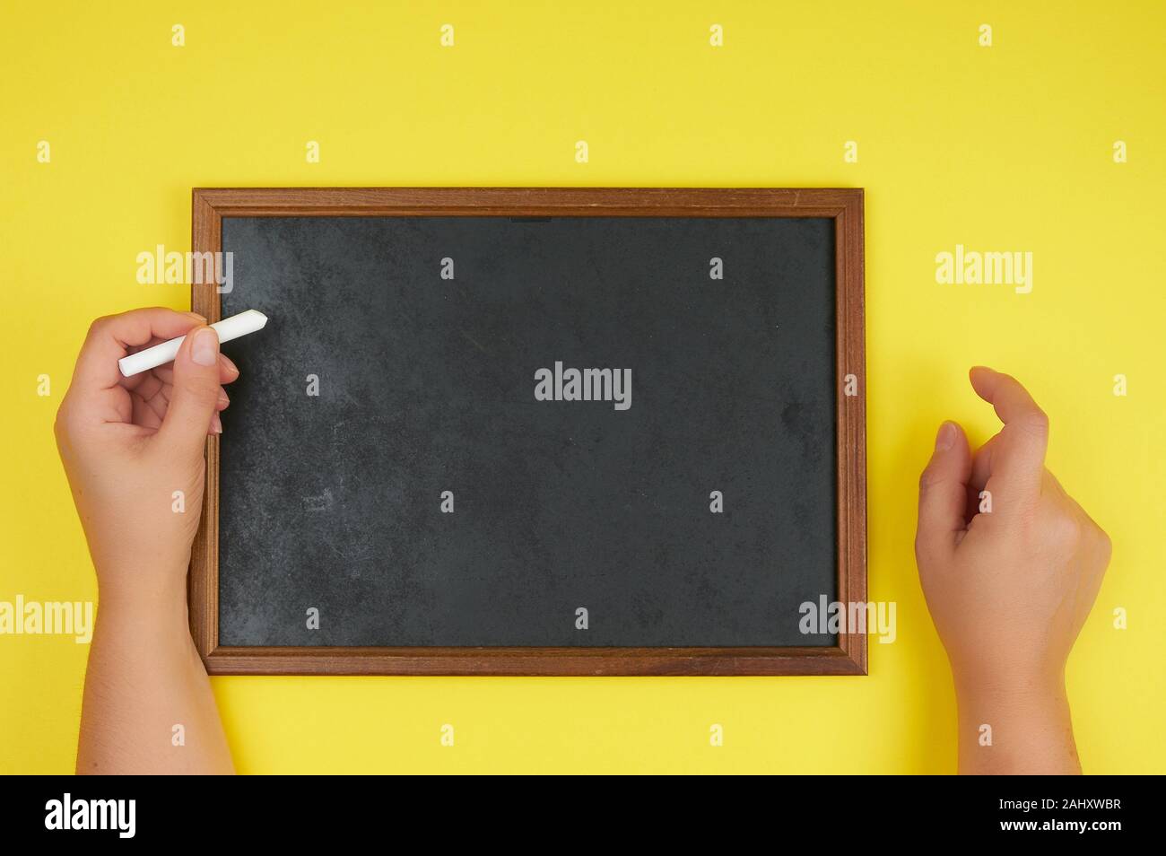 black chalk frame and two female hands with a piece of white chalk ...