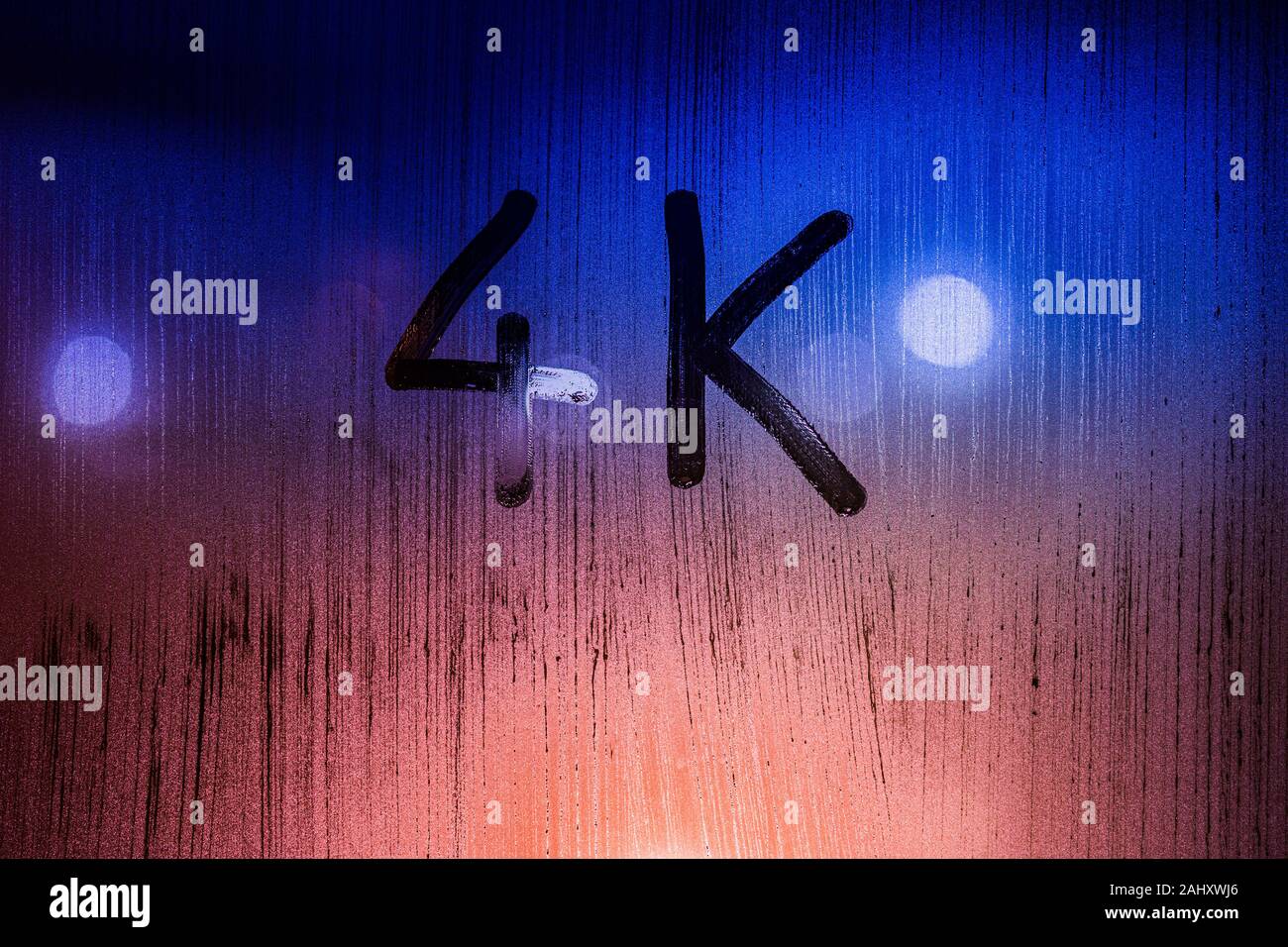 The word 4k handwritten on wet glass with blurred night lights in ...
