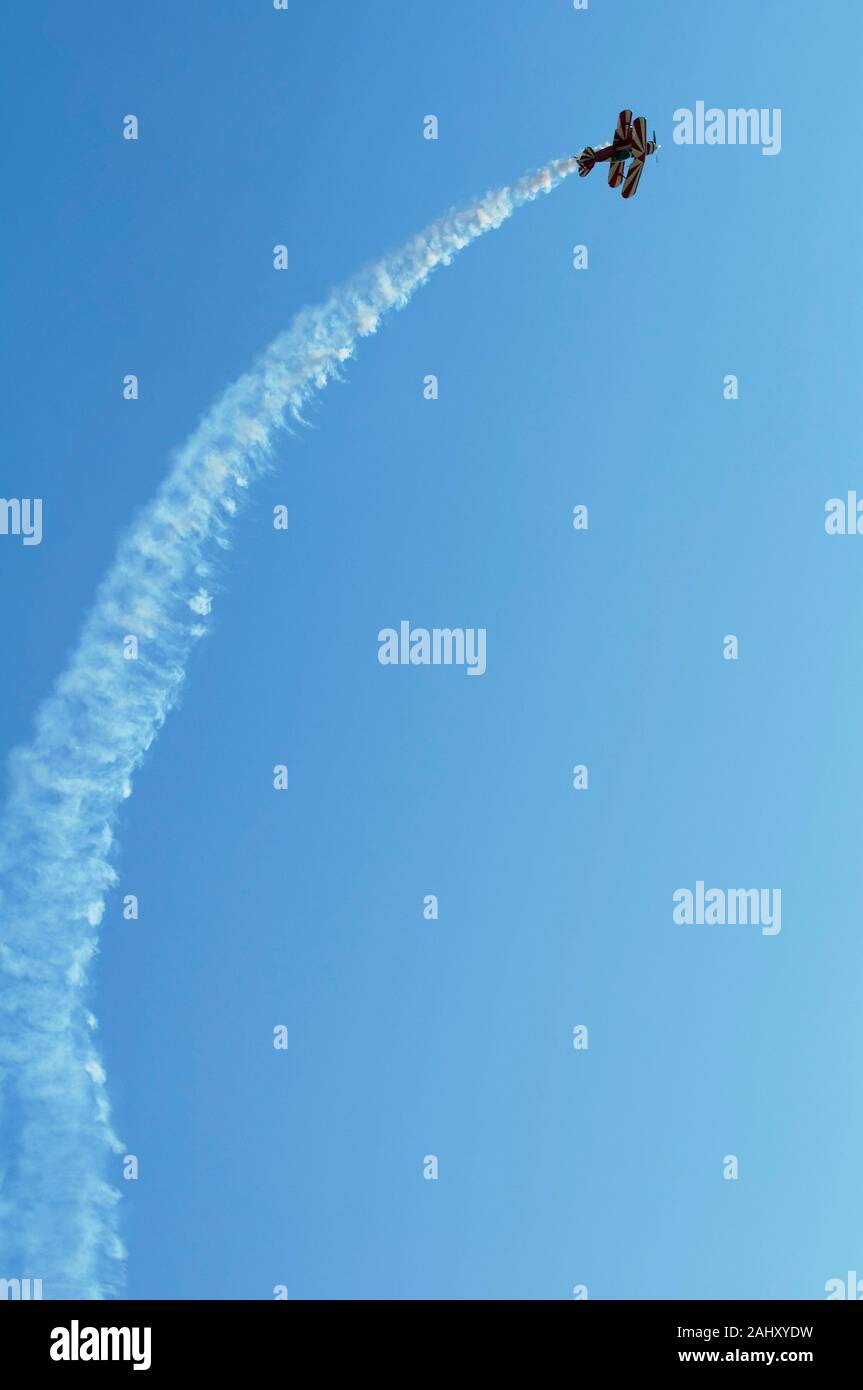 Red plane looping in a blue sky. Vertical image Stock Photo - Alamy