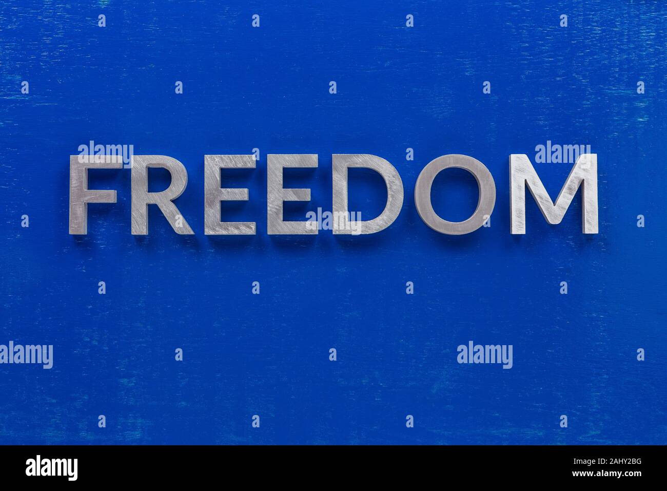 the word freedom laid with silver metal characters on blue painted ...