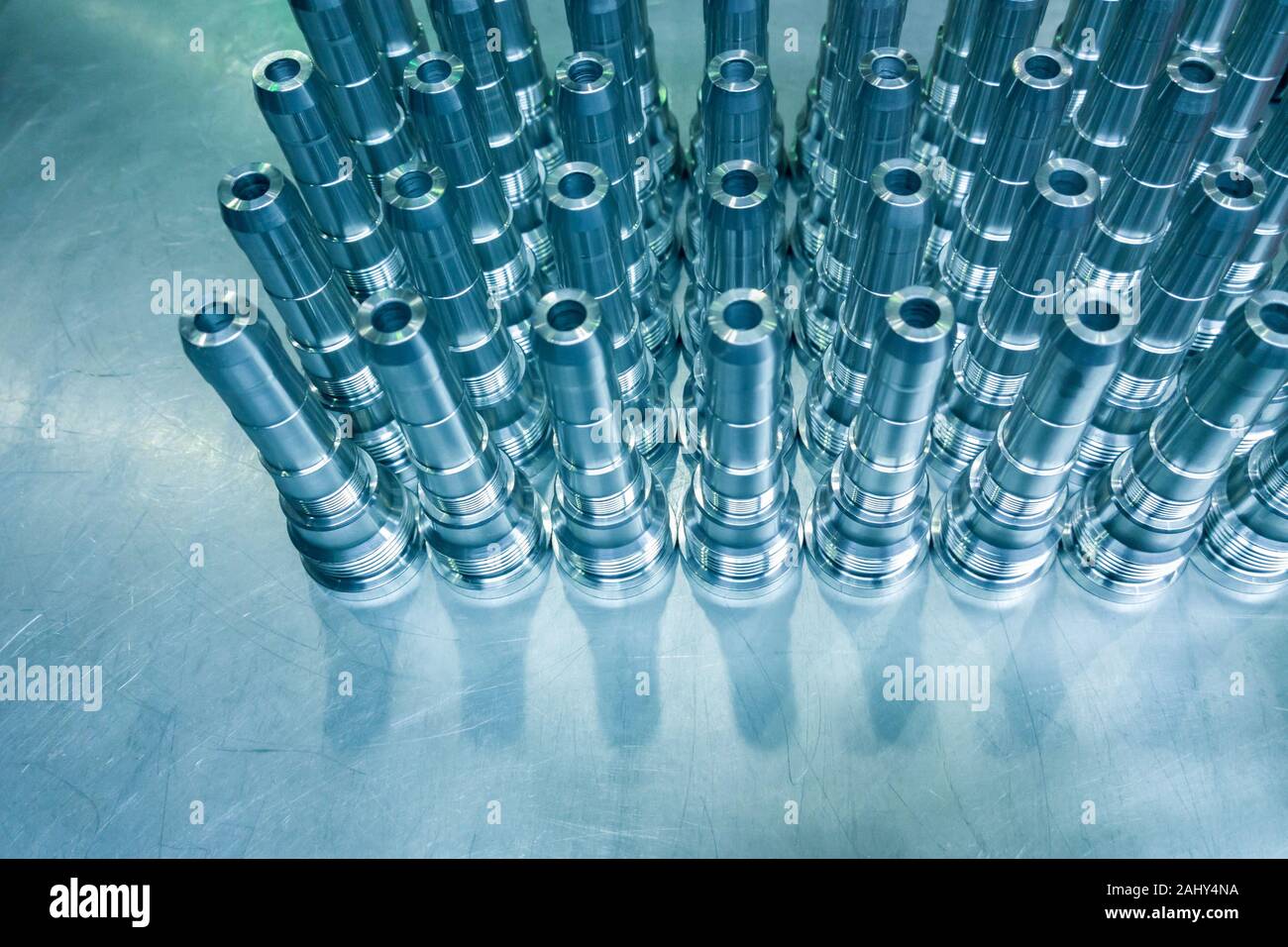 Shiny blue steel parts background, long clean steel threaded rods after ...