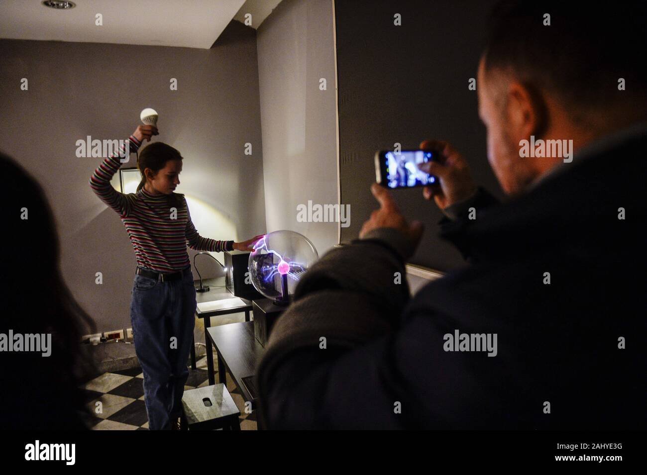 A visitor takes a photo of a girl interacting with an electric illusion ...