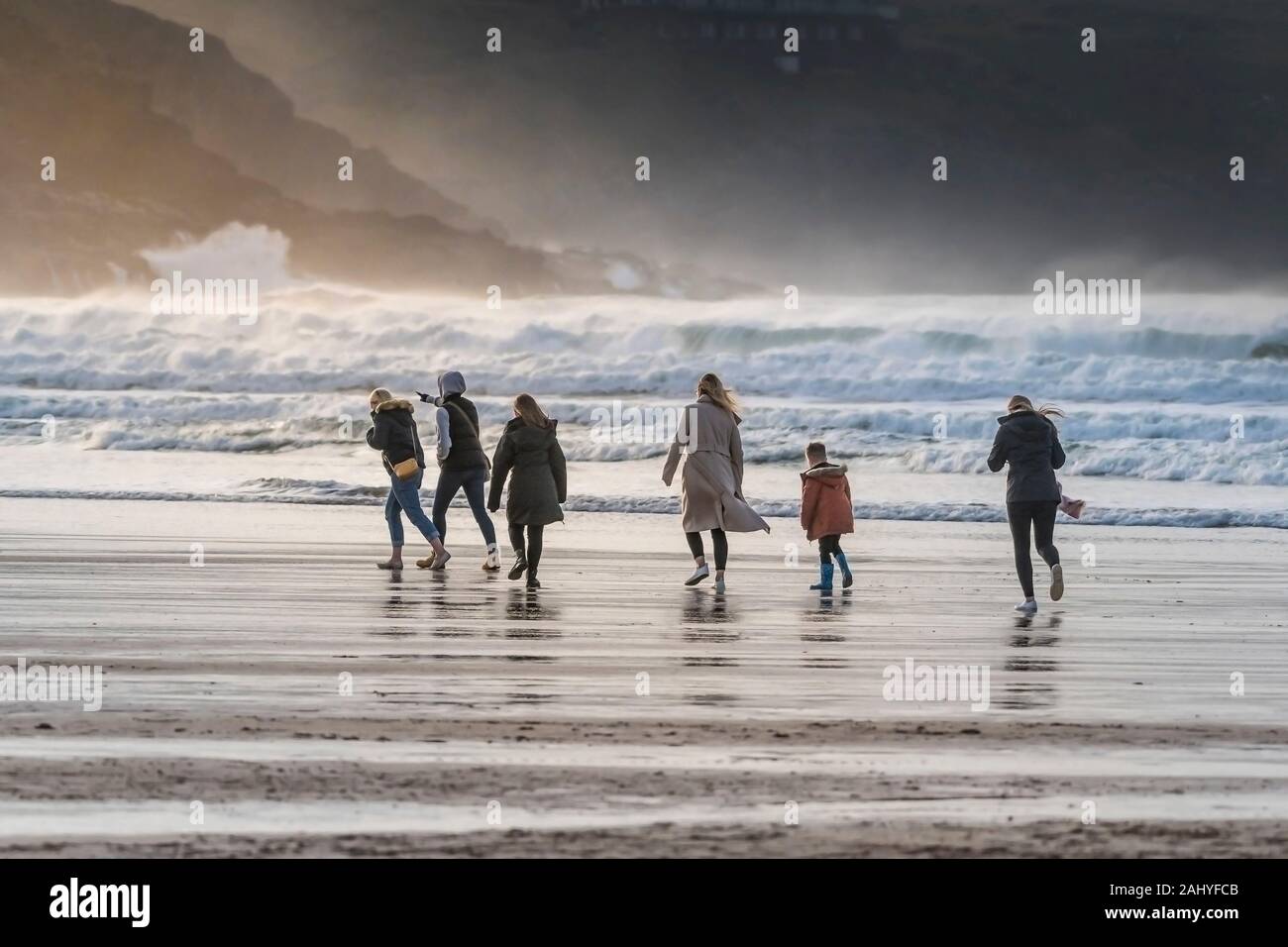 A group of young people walking in cold windy weather conditions across ...
