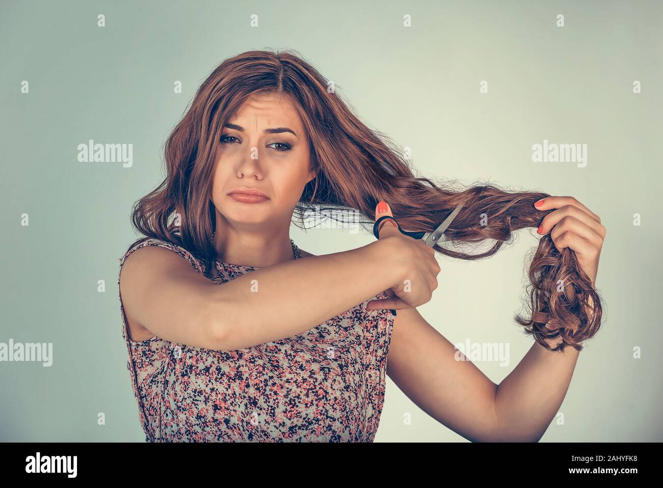 Frustrated sad woman almost cry holding her hair and scissors about to ...