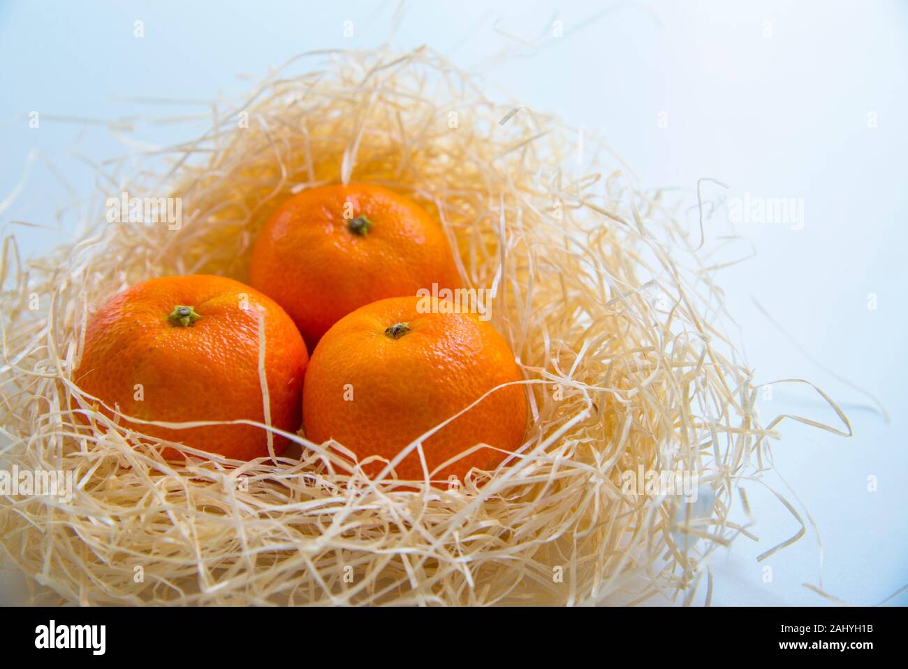 Three mandarins in a straw nest Stock Photo - Alamy