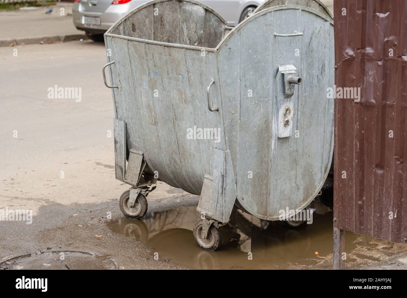 Empty waste container in a dirty puddle. A metal container without a ...