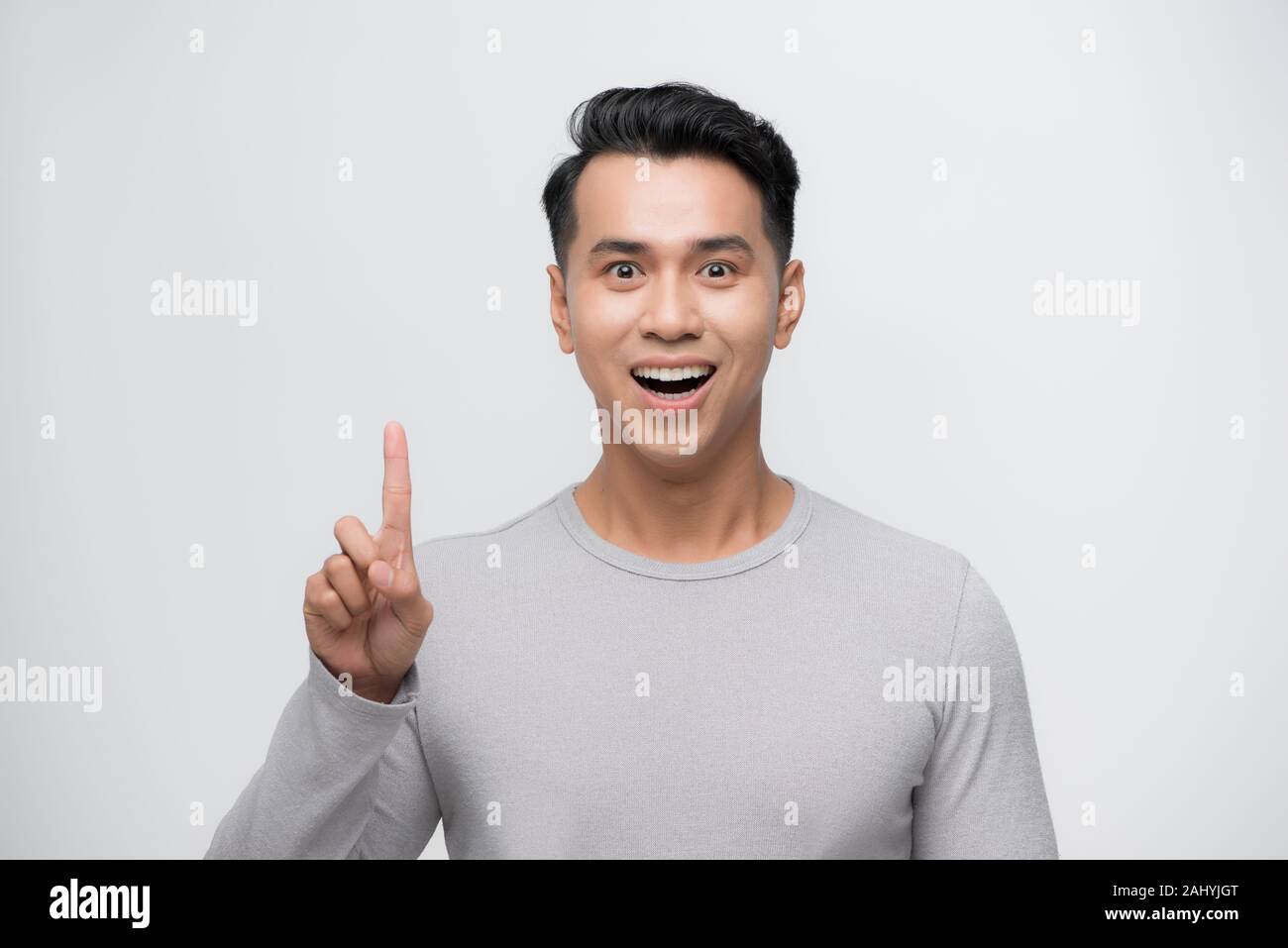 Smiling young man pointing up with a new idea over white background ...