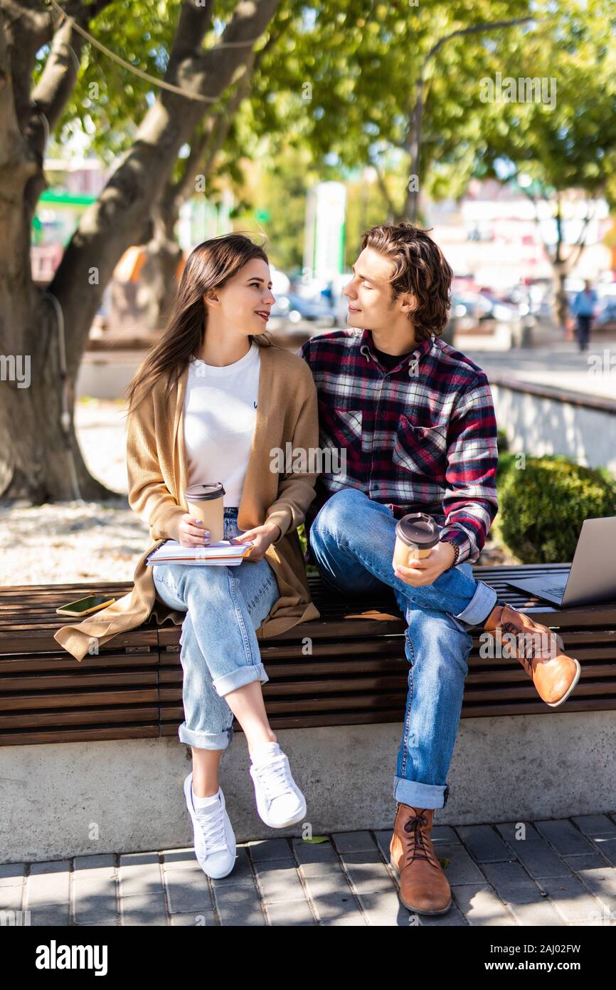 Beautiful loving couple sitting on the bench in the park, drinking ...