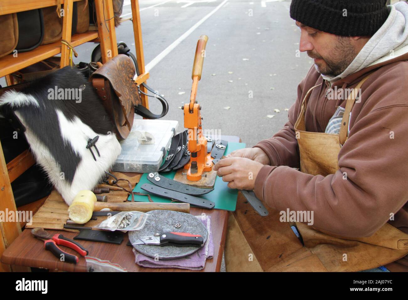 Working process of leather craftsman. Tanner or skinner sews leather or ...