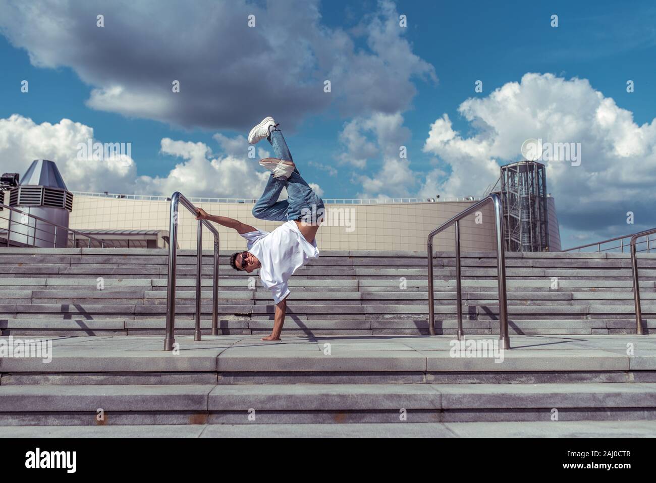 strong male dancer, standing on one arm in jump, dancing breakdance ...