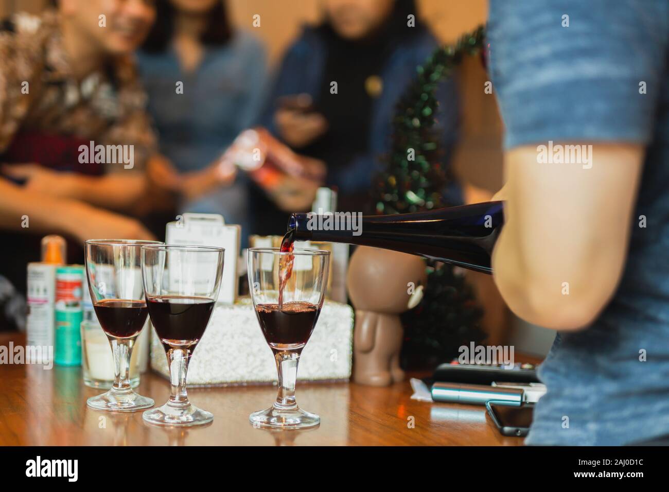 Hand pouring red wine in glass during party with friends Stock Photo ...